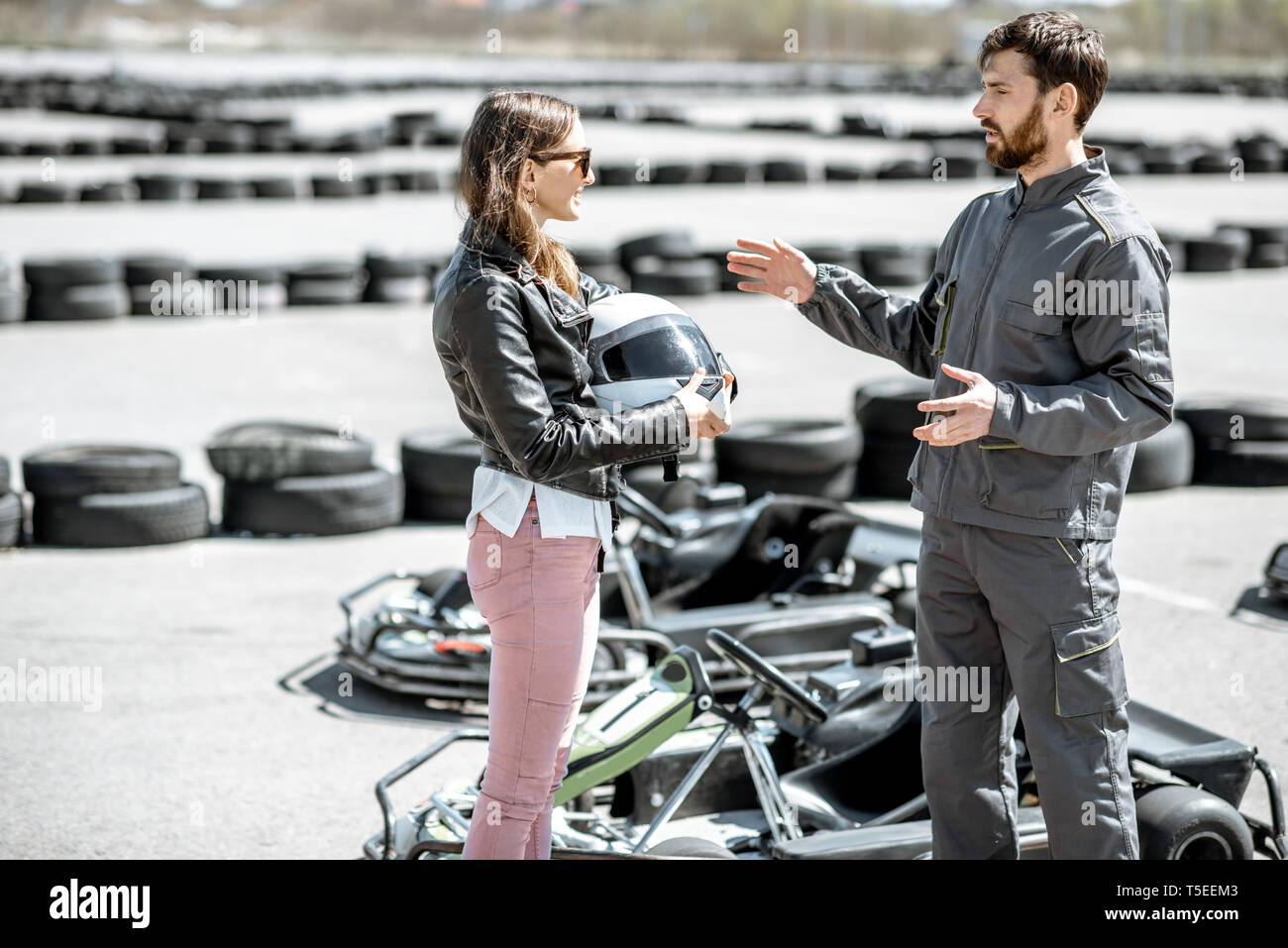 Male instructor in sportswear talking with young woman driver standing ...
