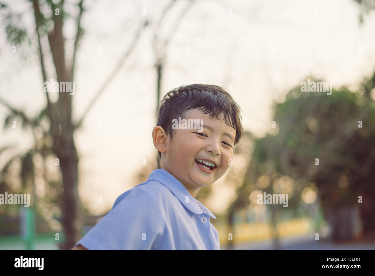 Outdoor portrait of a happy Asian student kid in school uniform smiling ...