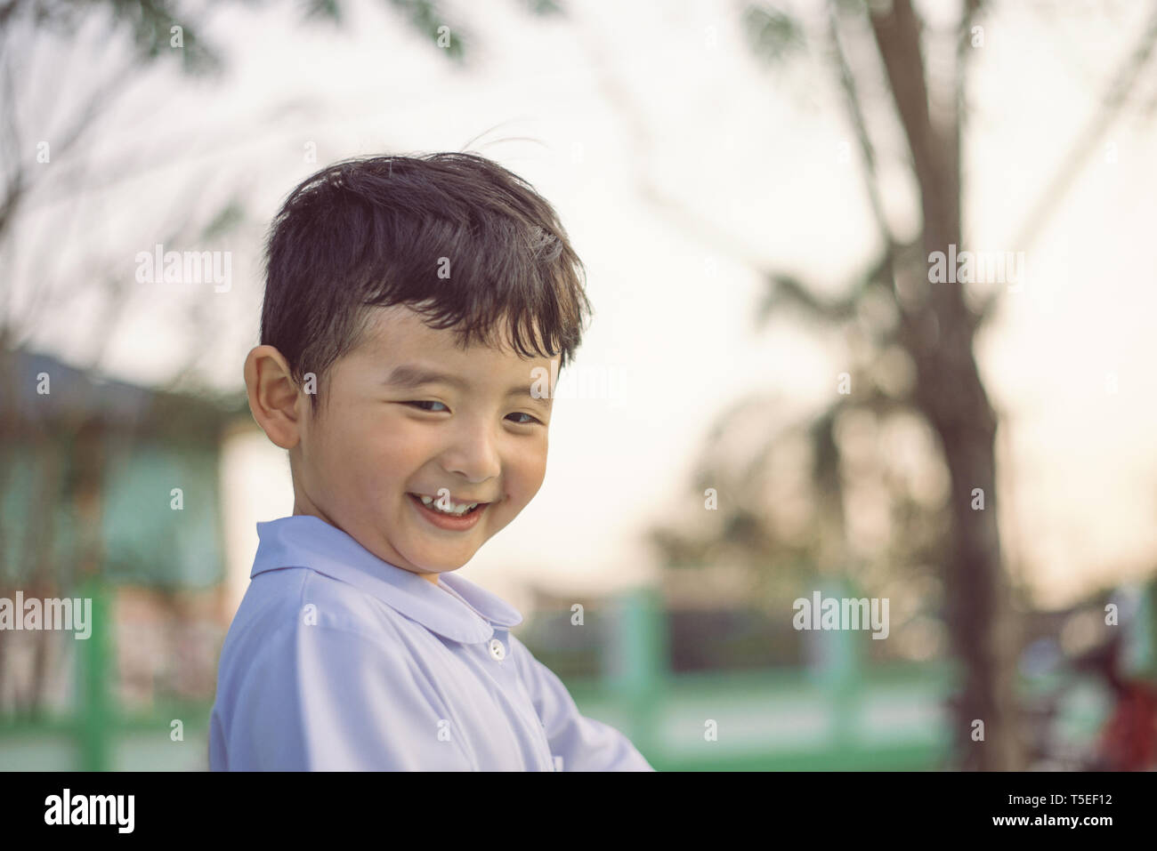 Outdoor portrait of a happy Asian student kid in school uniform smiling with copy space for add ...