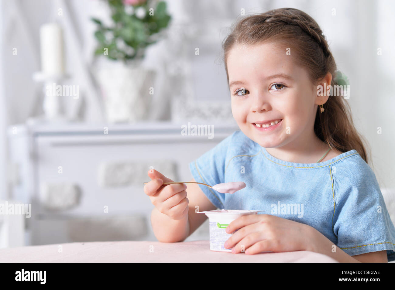 Cute little girl eating delicious yogurt at home Stock Photo - Alamy