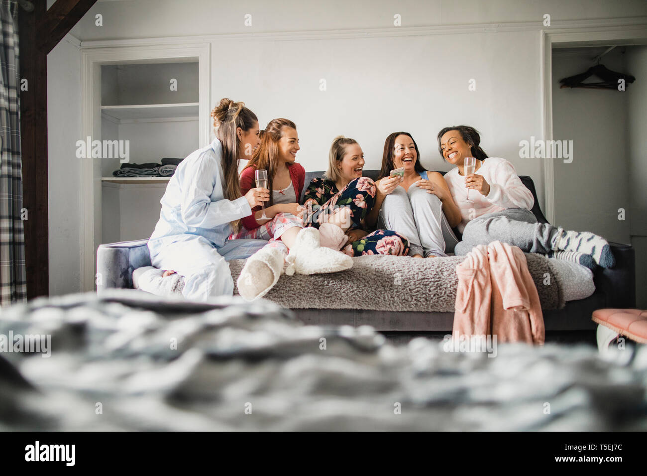 Small group of female friends sitting in a bedroom on a weekend away ...