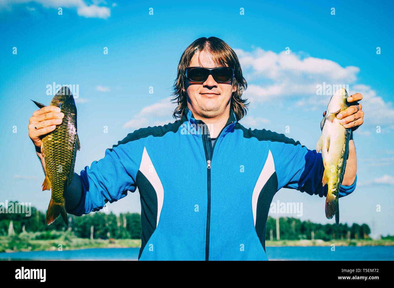 Happy fisherman showing caught fish. Caucasian man holds two fish ...