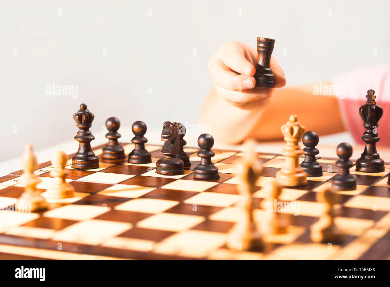 Little caucasian girl holding a black castle in the hand. The chess ...