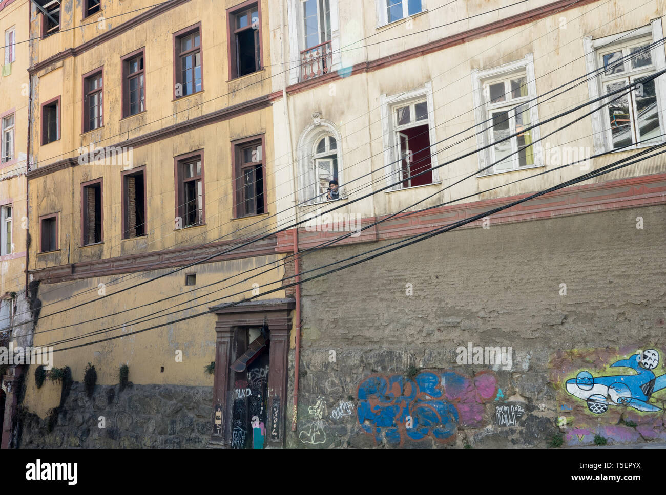 Young man looking out of a window of a tall building beside a derelict ...