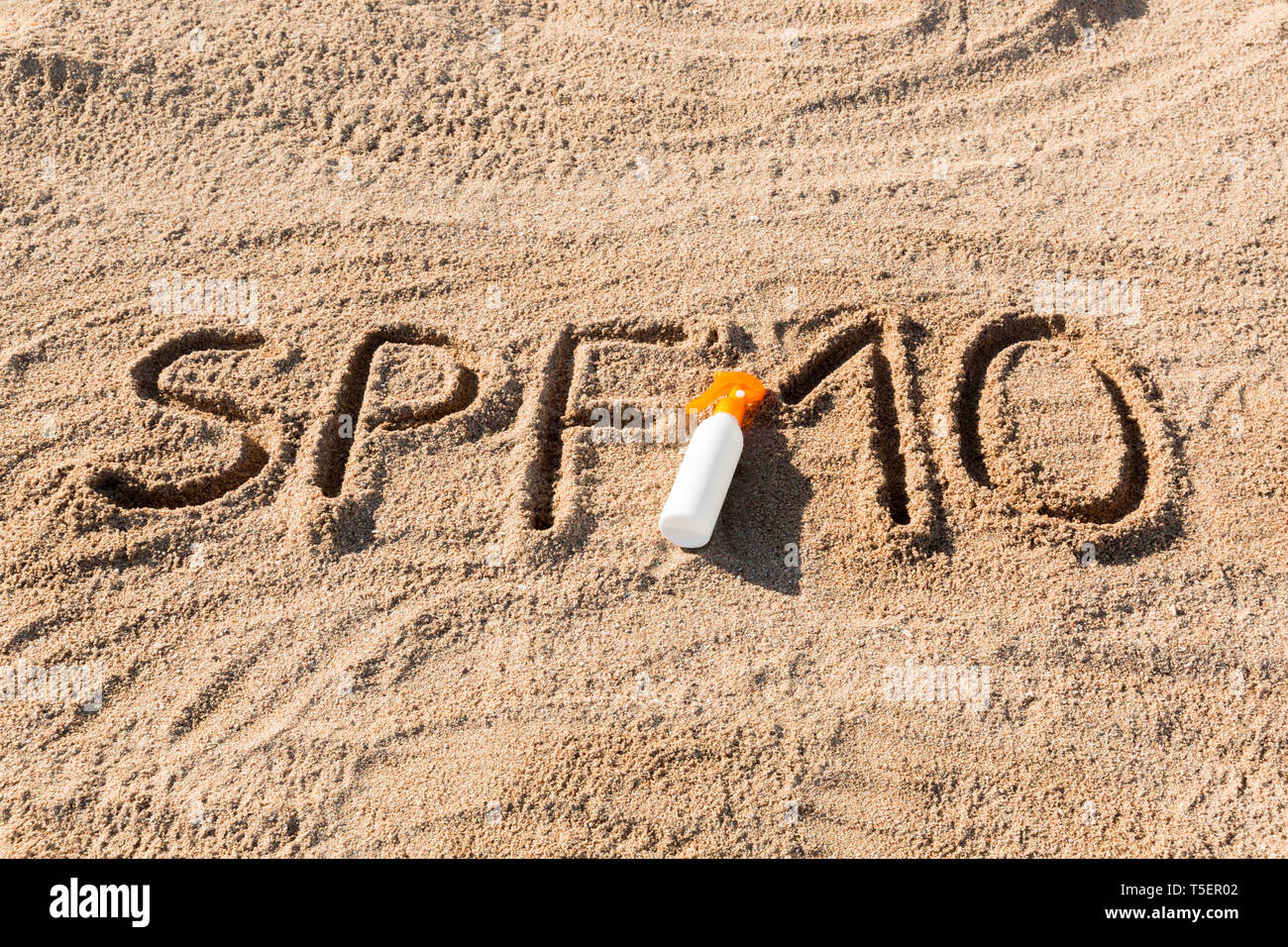 Sun protect factor ten. SPF 10 word written on the sand and white ...