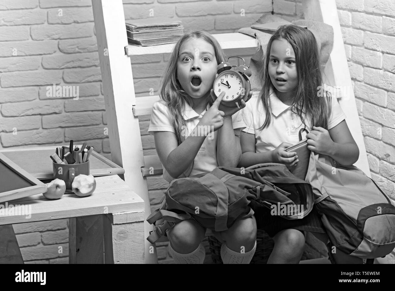 Late. Shoked small girls show time on clock. small kids late to school ...