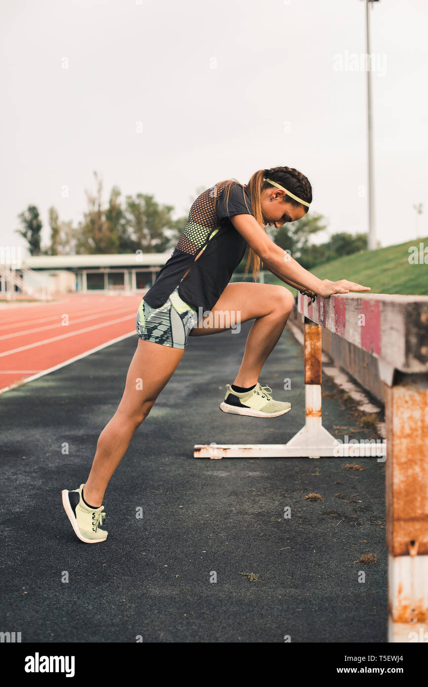 Female athlete doing warm-up exercises on tartan track Stock Photo - Alamy