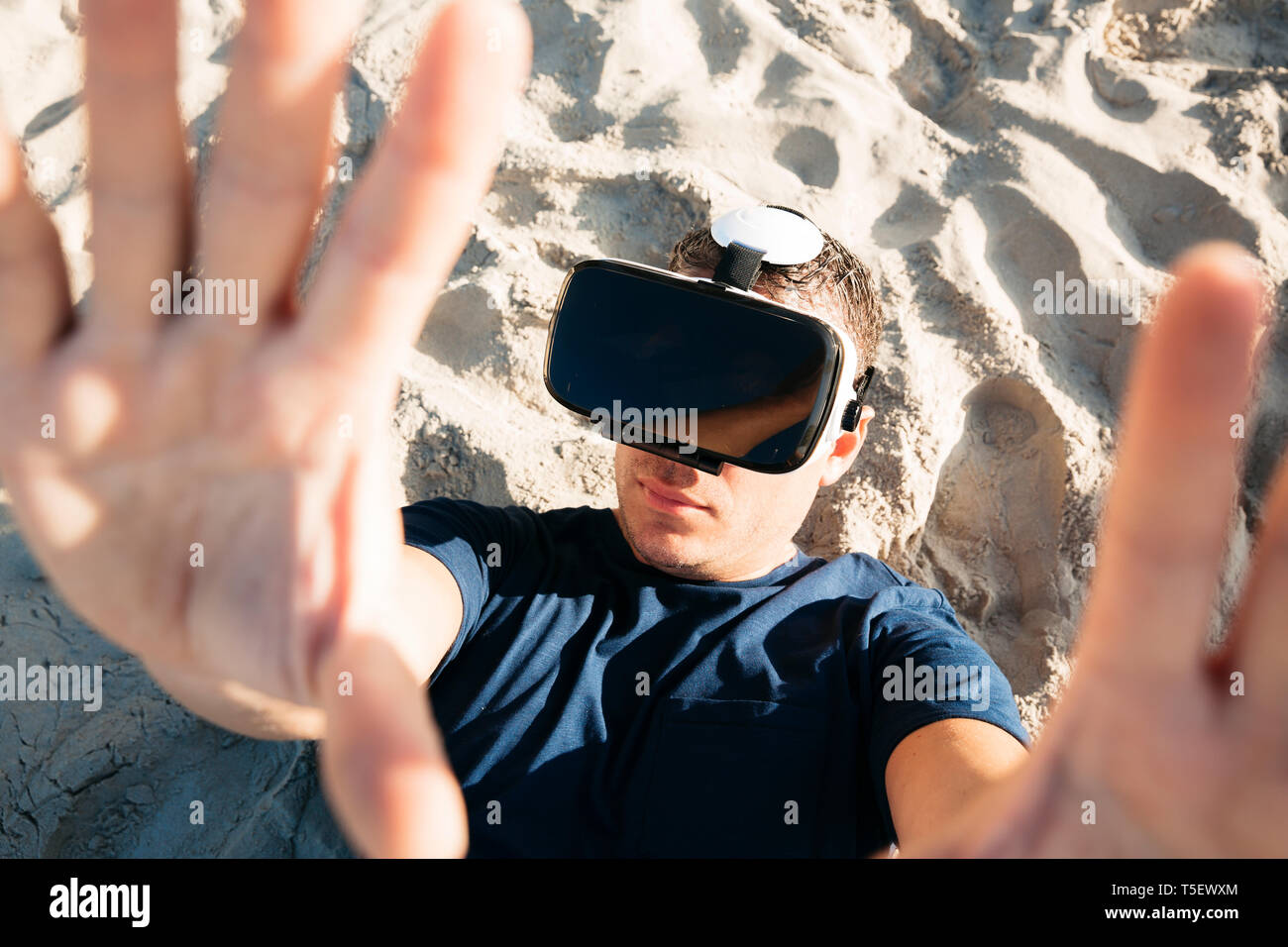 Man wearing VR glasses lying in sand on the beach Stock Photo - Alamy