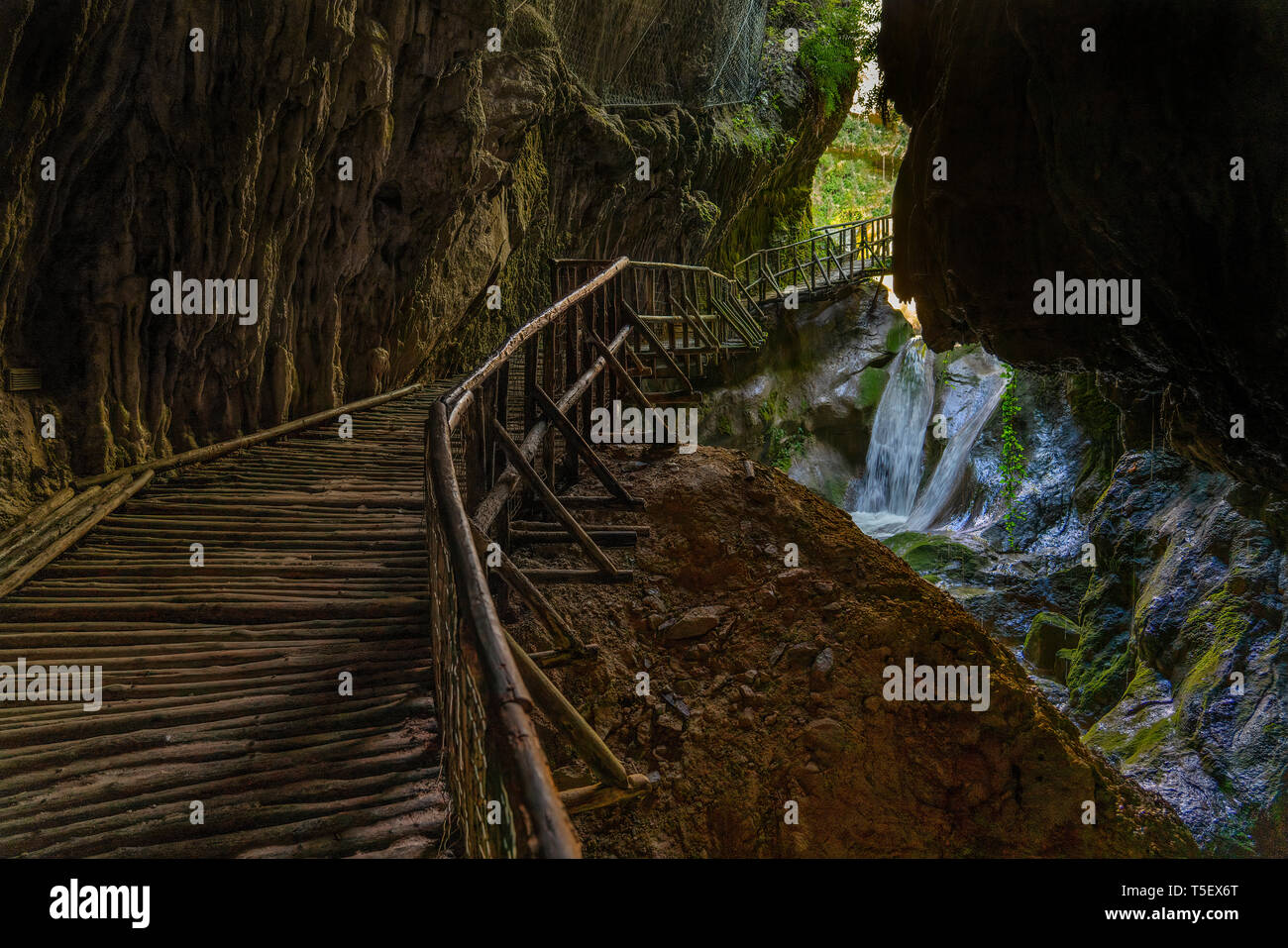 Italy, Veneto, Caglieron caves, Waterfall and wooden trail in the caves ...