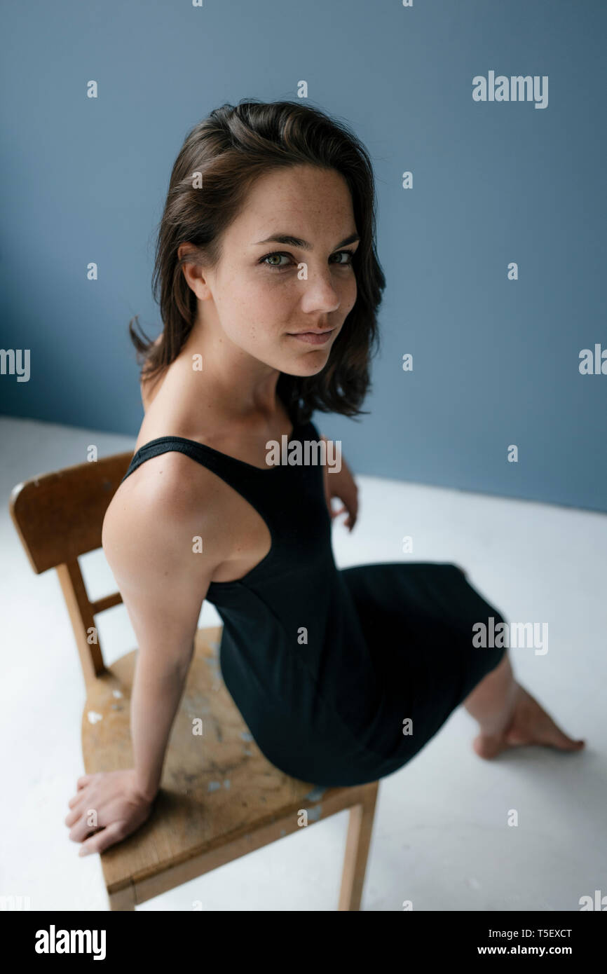 Woman sitting on chair, wearing black dress Stock Photo - Alamy