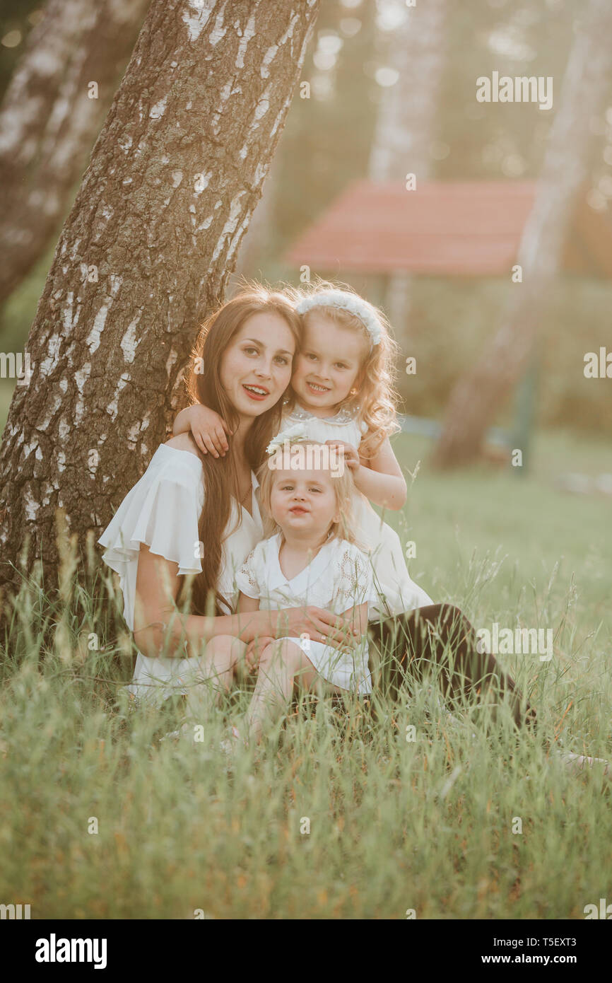 Mother and two daughters whirling. Mother holds daughters on hands. Family time together. a ...