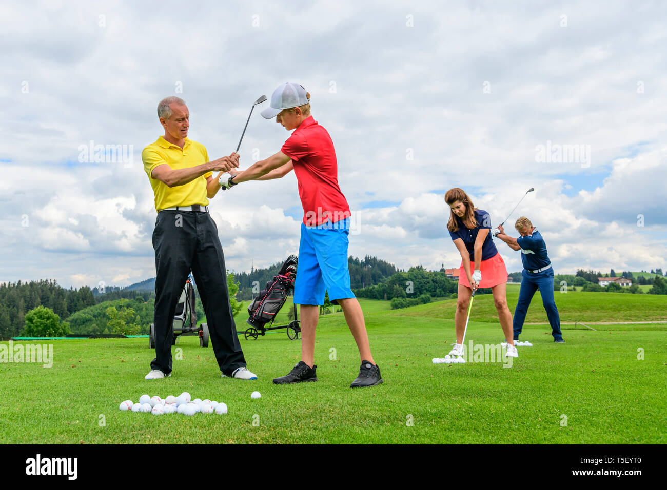 Golf players practising with golf pro on drivingrange Stock Photo - Alamy