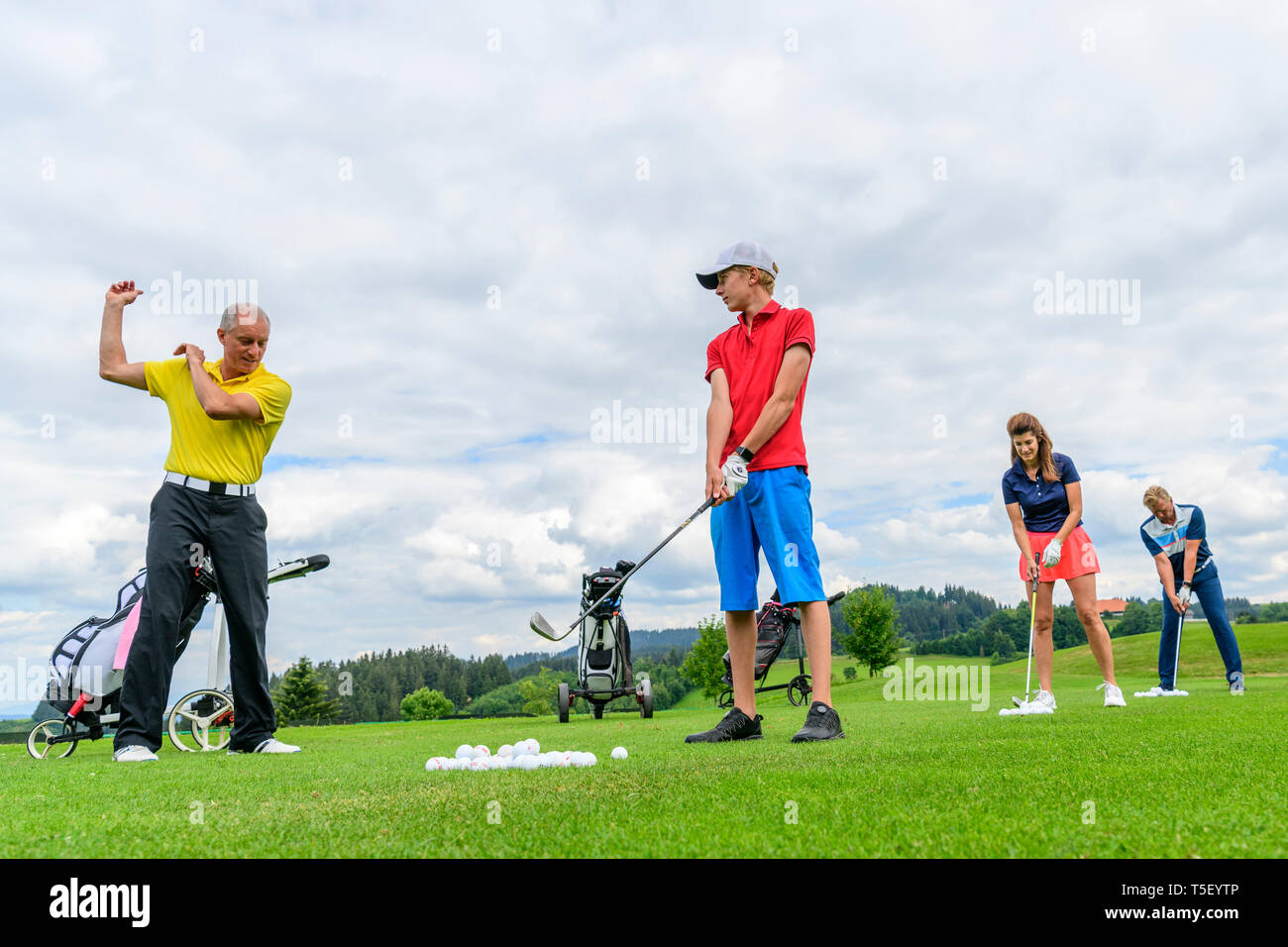 Golf players practising with golf pro on drivingrange Stock Photo - Alamy