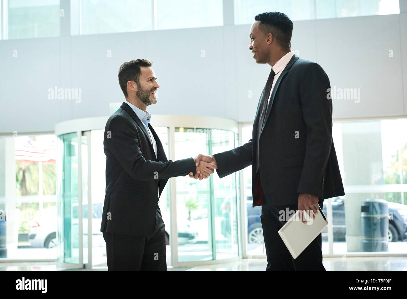 Businessmen shaking hands in hotel lobby Stock Photo - Alamy