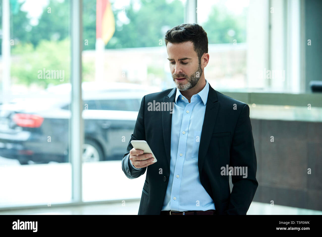 Businessman using smart phone in hotel lobby Stock Photo - Alamy