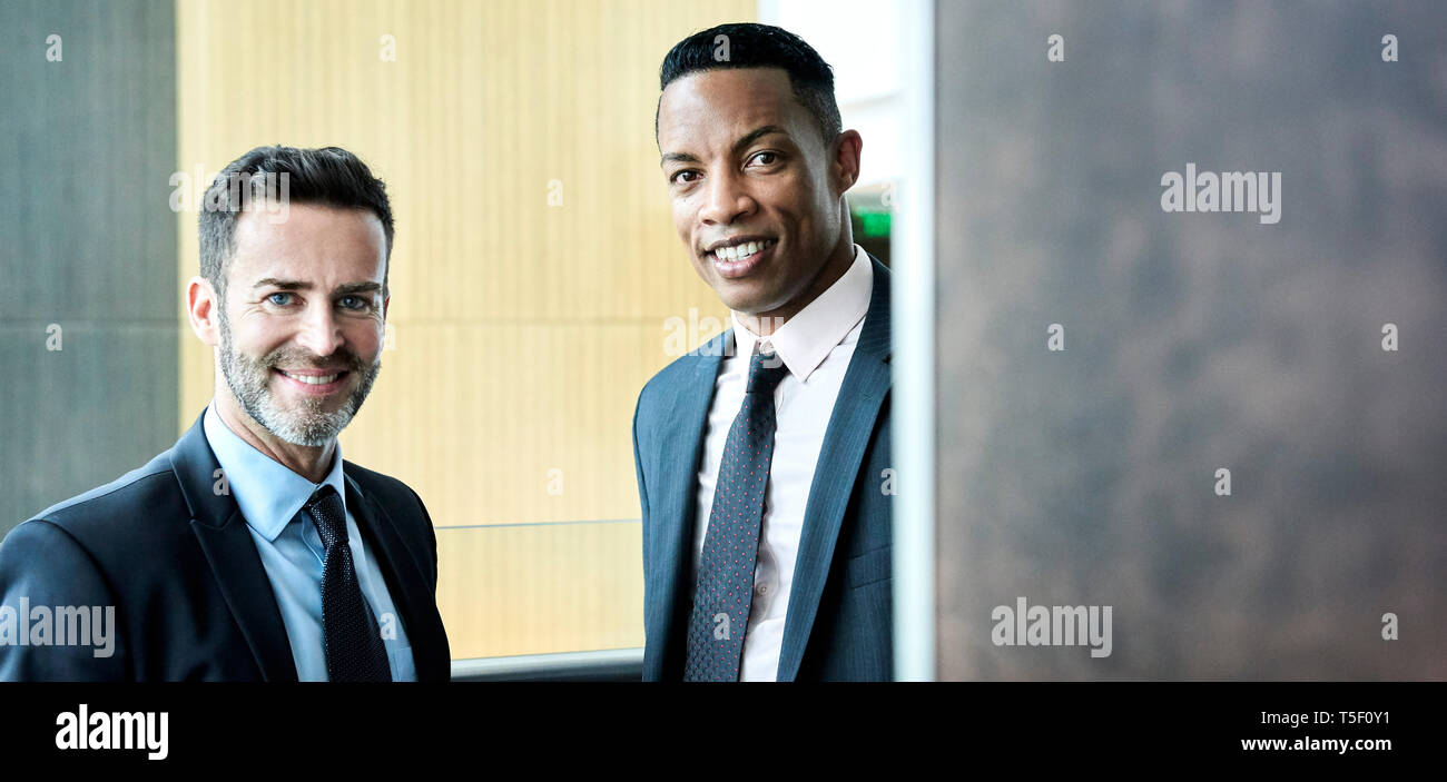Smiling businessmen standing in hotel lobby Stock Photo - Alamy