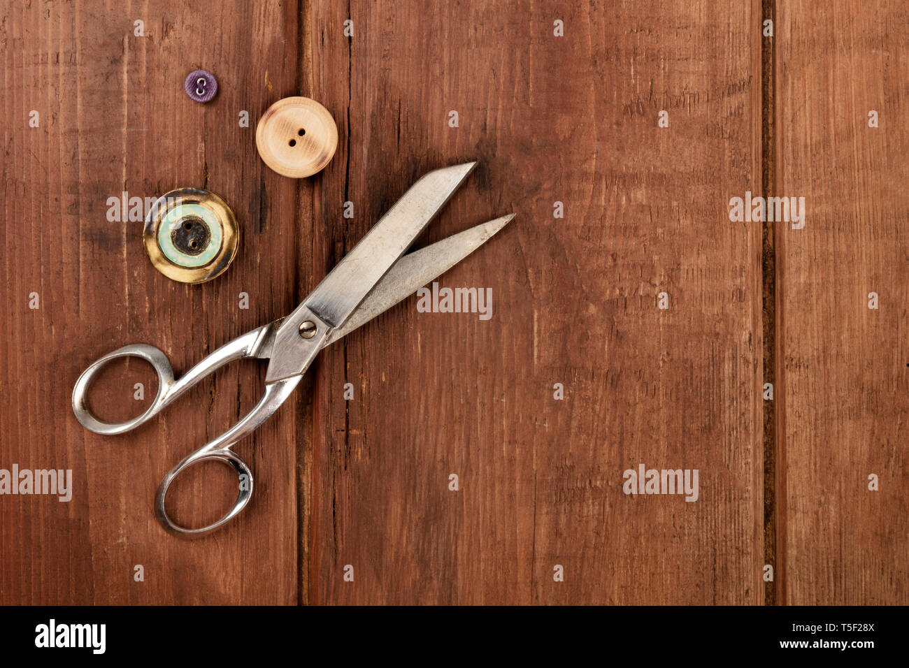 Vintage scissors and buttons, shot from the top on a dark rustic wooden ...