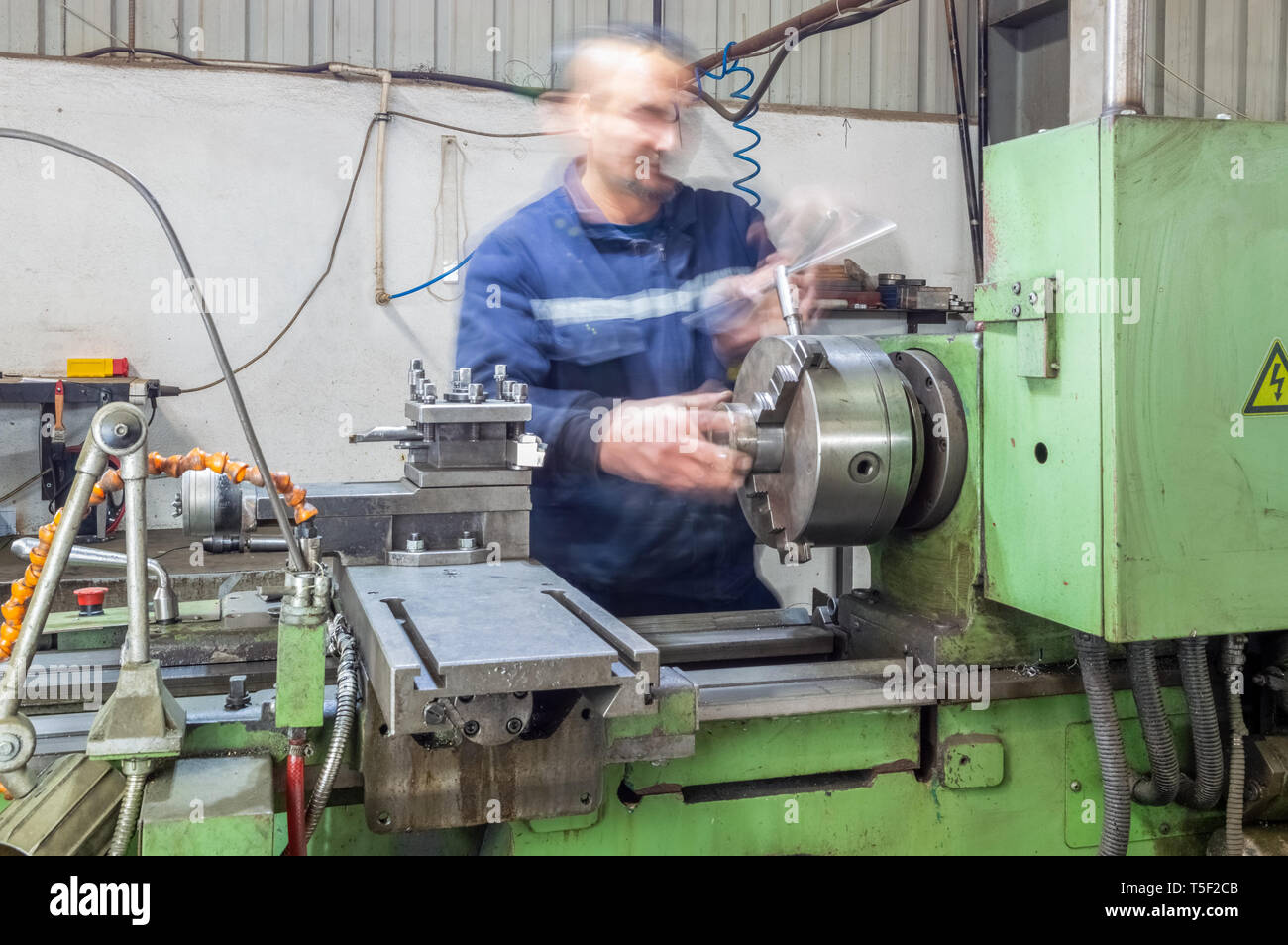 Blue-collar machine operator working with lathe machine in a factory ... Blue-collar machine operator working with lathe machine in a factory ...