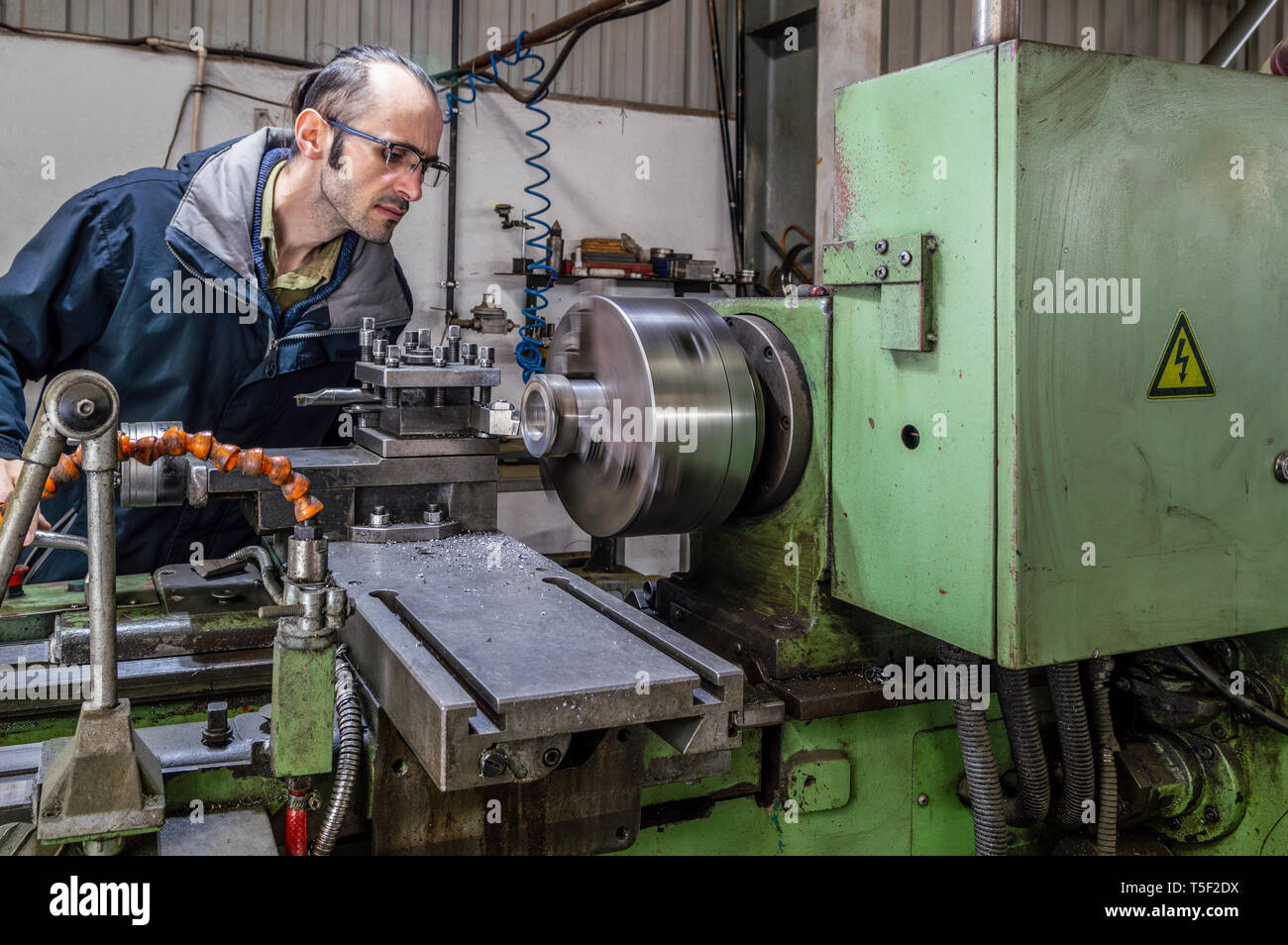 Caucasian engineer watching the headstock of turning lathe machine in a ...