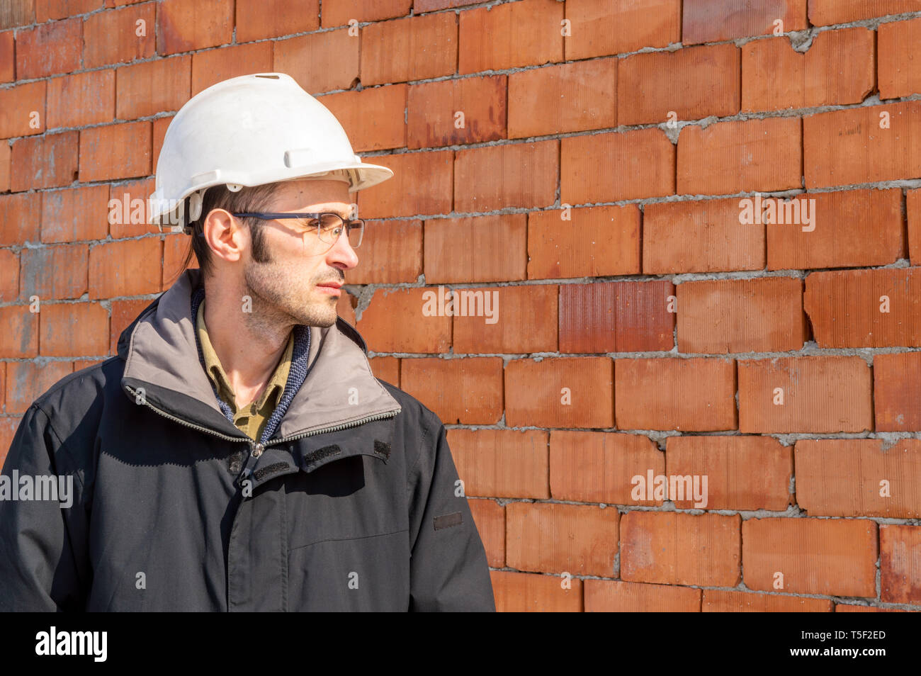 Portrait of a young civil engineer wearing hardhat on construction site ...