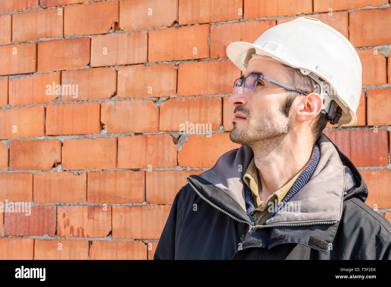 Portrait of a young civil engineer wearing hardhat on construction site ...