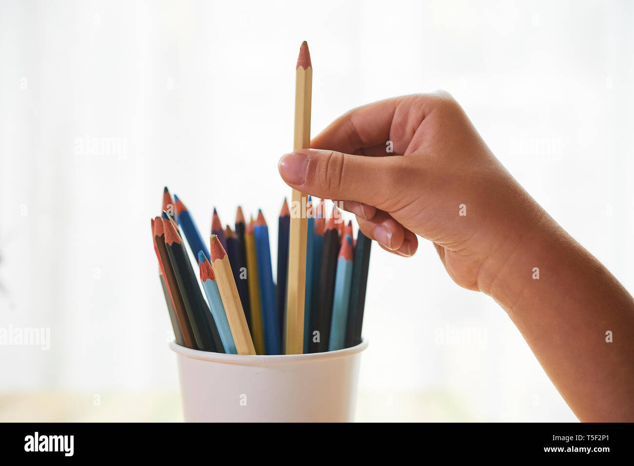 Girl taking colored pencil Stock Photo - Alamy