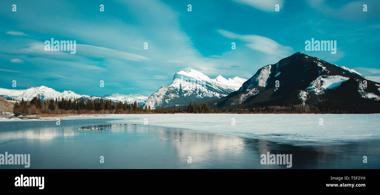 Panorama of Mount Rundle mountain peak with blue sky reflecting in ...