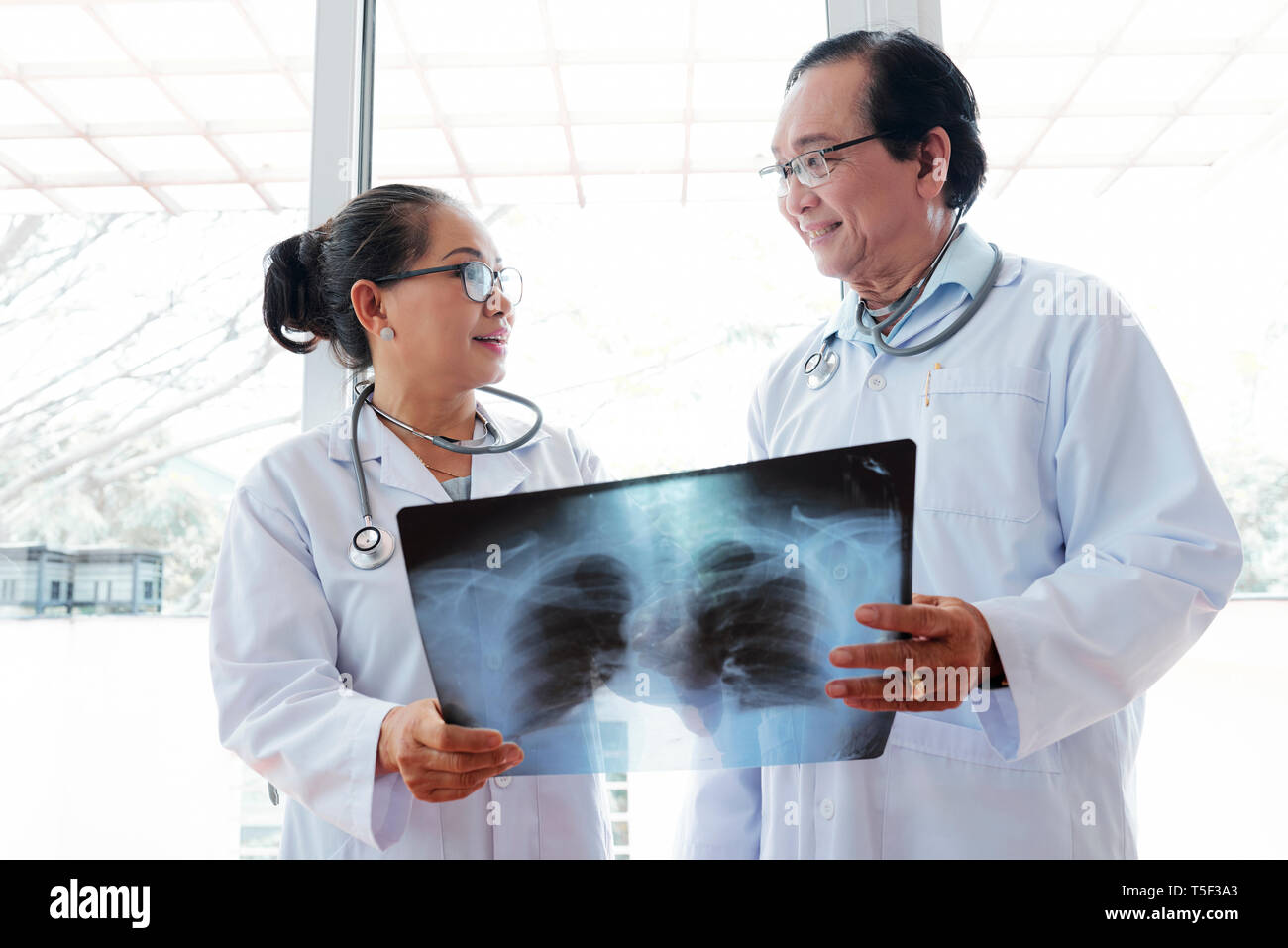 Smiling doctors with x-ray of recovered patient Stock Photo - Alamy