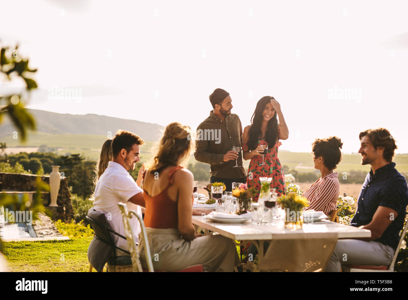 Couple at a party announcing their marriage to friends sitting around ...
