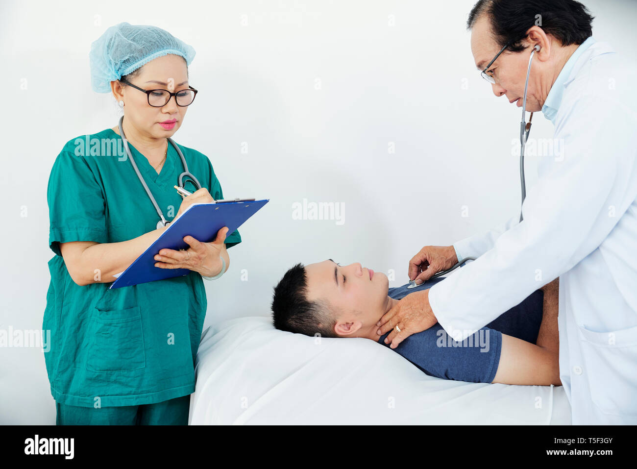 Doctor and nurse examining patient Stock Photo - Alamy