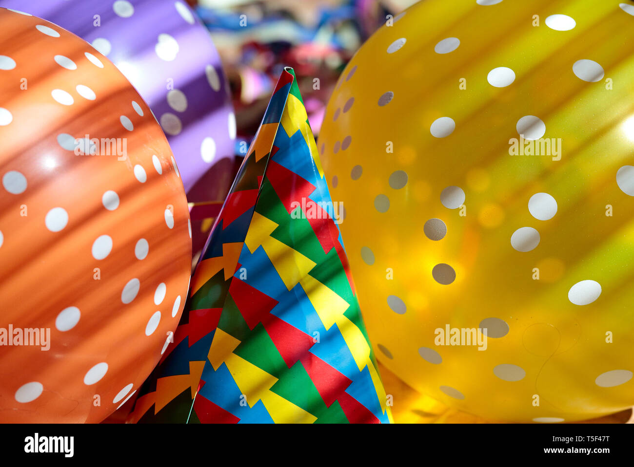 Colourful dotted balloons and paper hat in bright light in first of may ...