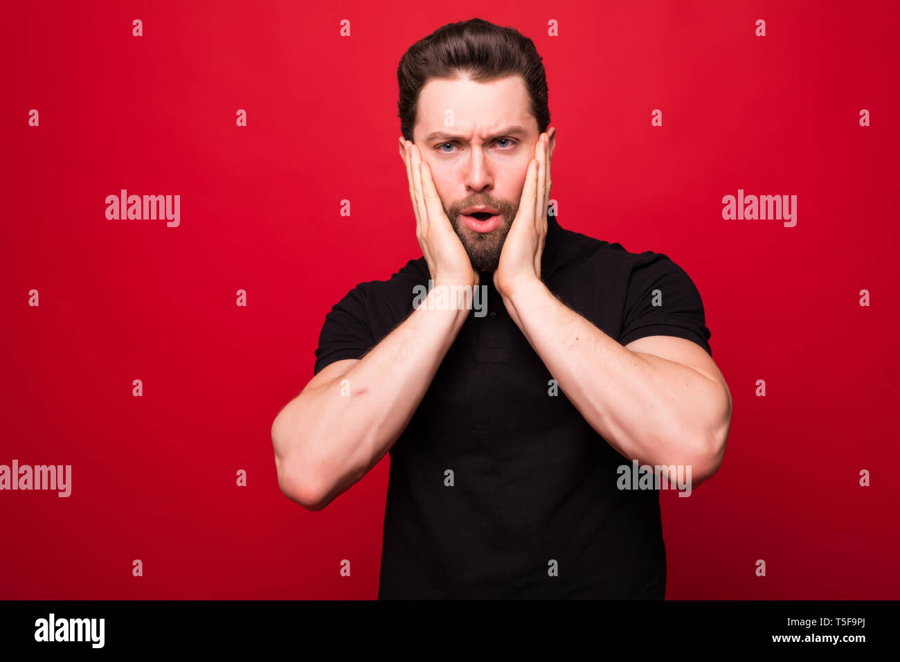 Picture of shocked young handsome man standing isolated over red wall ...