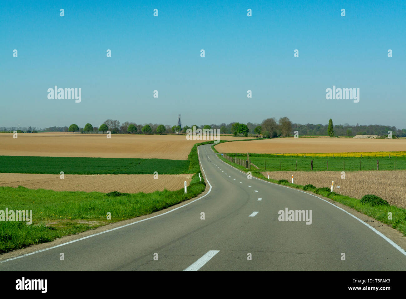 Asphalt road and spring landscape with farmers plowed fields and green ...