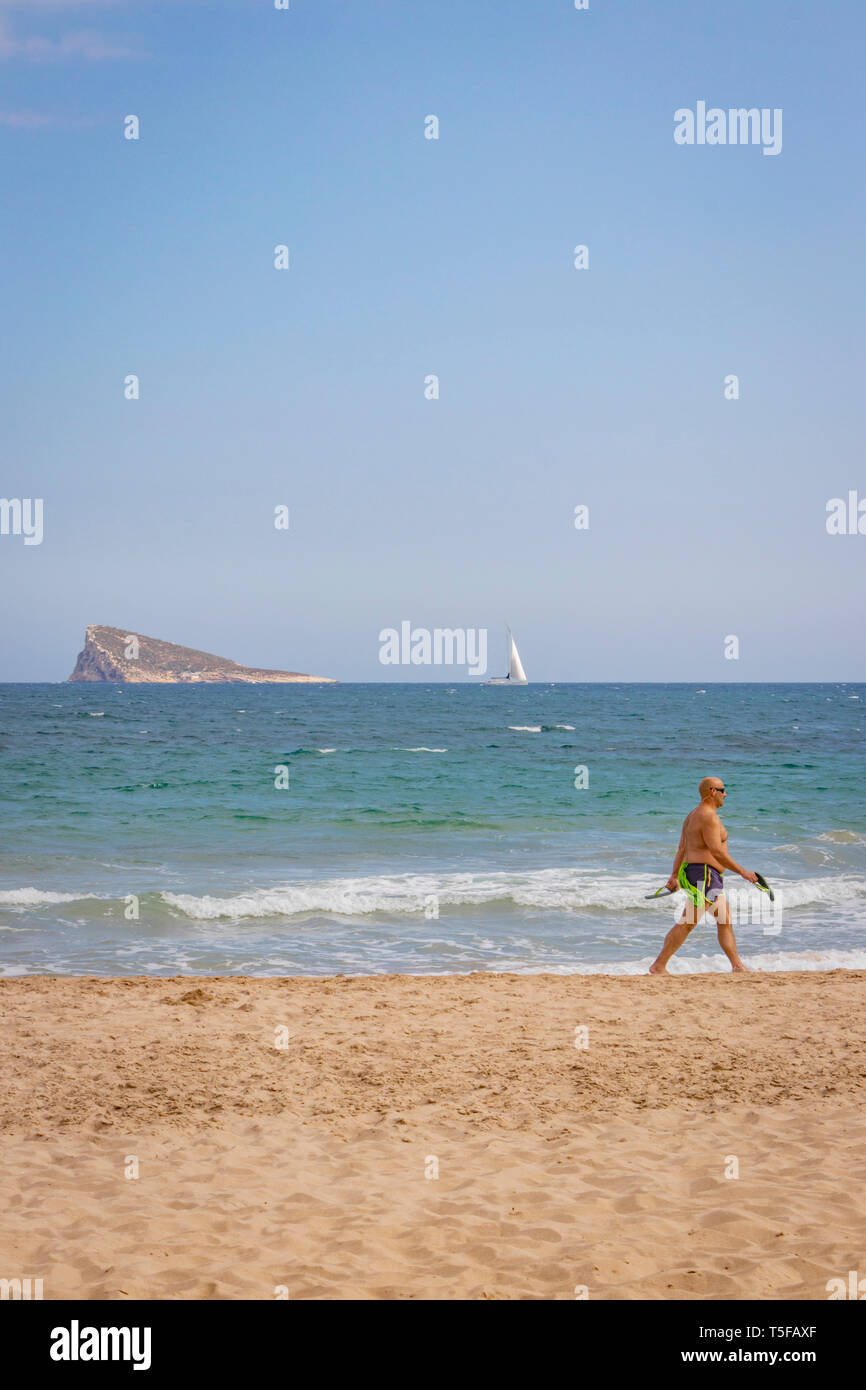 older man in trunks walks along seashore by the beach in Benidorm Spain ...