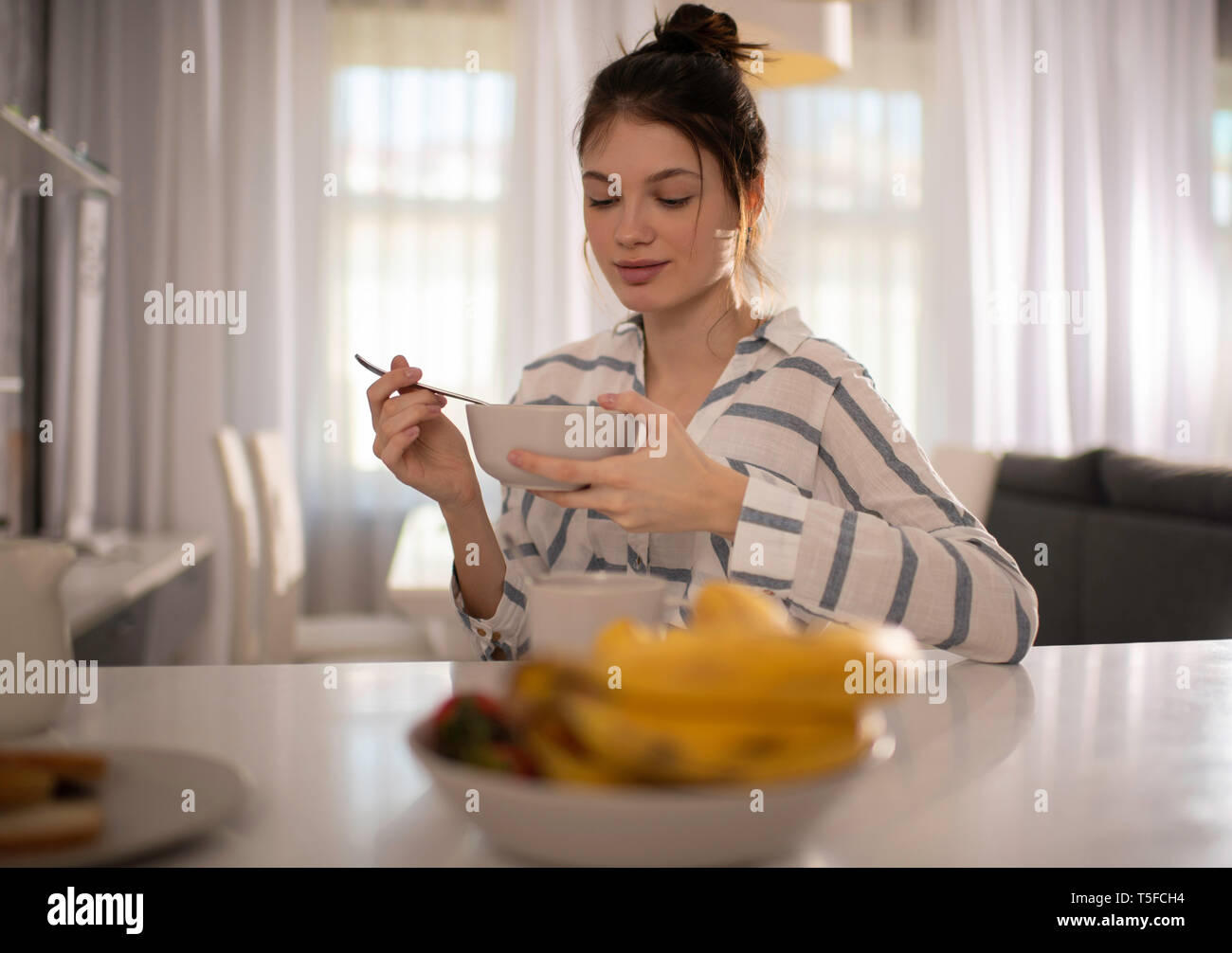 A portrait of a Woman Eating A Healthy Breakfast At Home in her kitchen ...