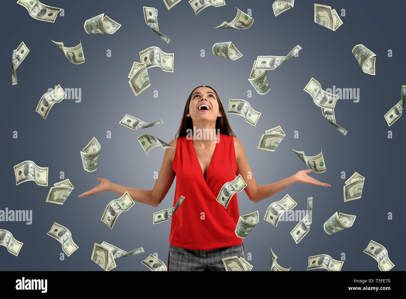 Happy rich woman with falling dollar banknotes on grey background Stock ...