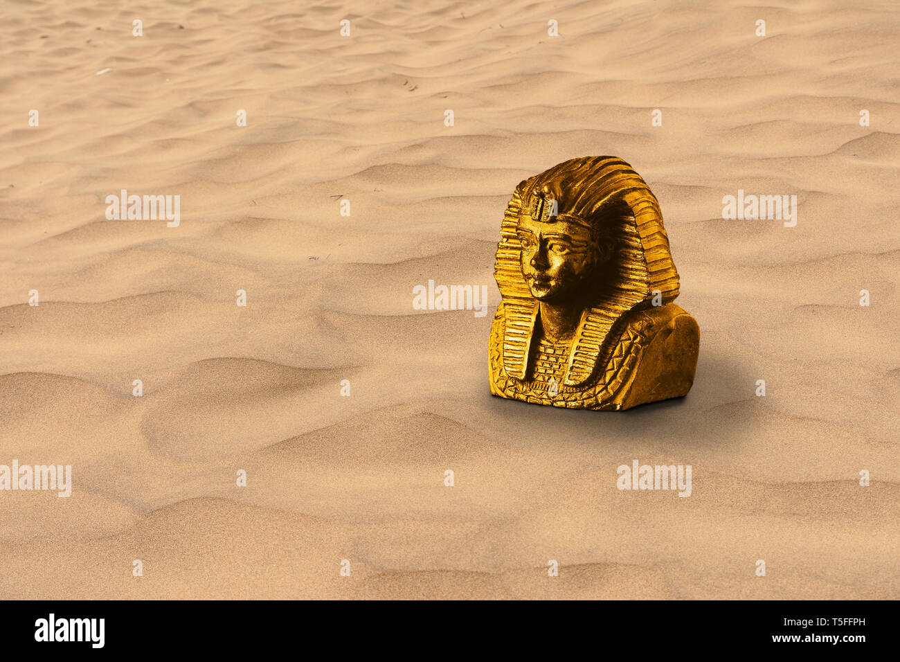Pharaoh's golden statue on sand Stock Photo - Alamy