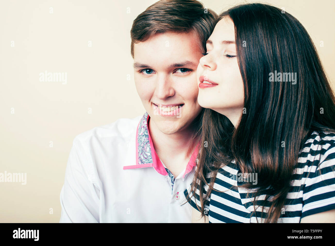 couple of happy smiling teenagers students, warm colors having a kiss ...