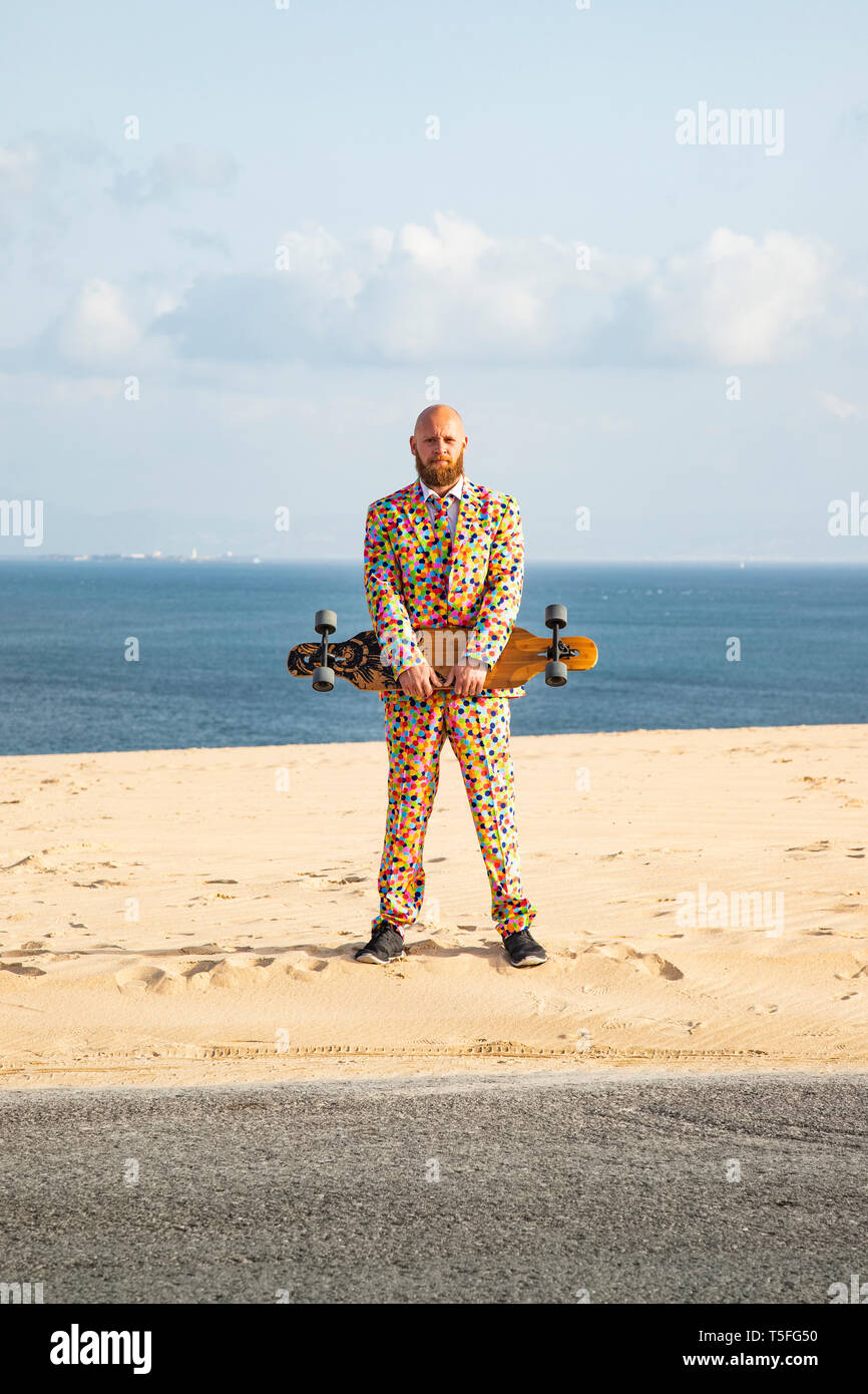 Bearded man with longboard wearing suit with colourful polka-dots ...