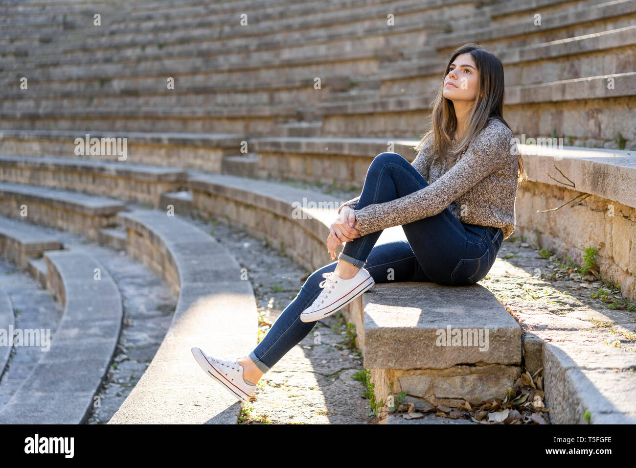 Young woman sitting on stairs outdoors looking around Stock Photo - Alamy