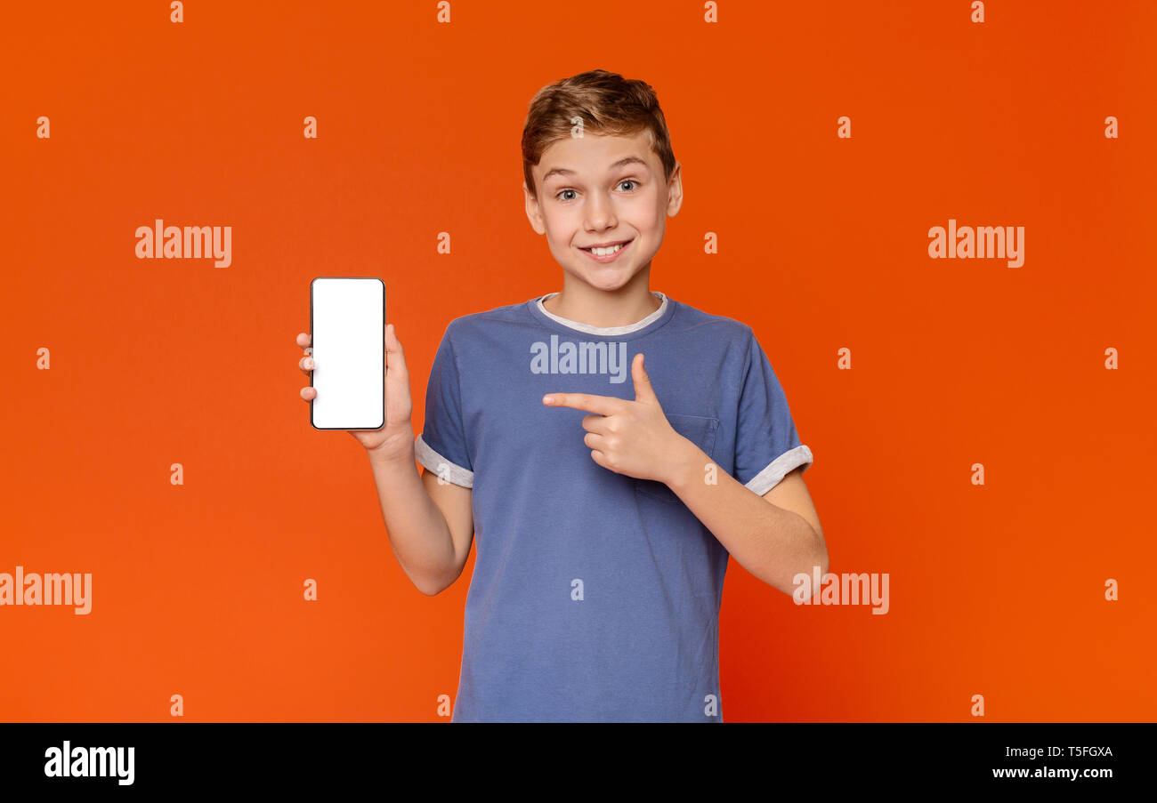 Emotional teen boy pointing at white mobile screen and smiling Stock ...