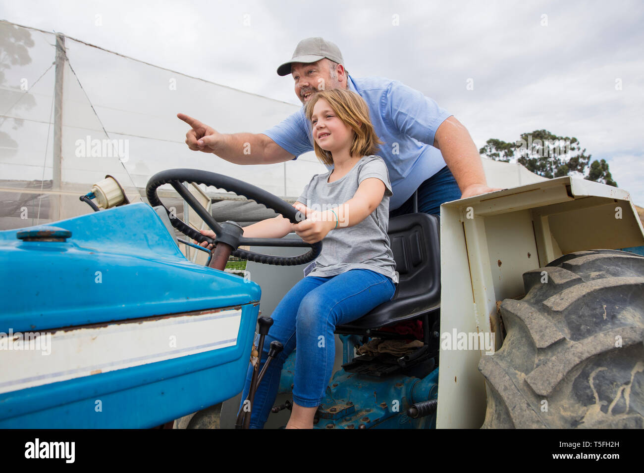 Farmer showing his daughter, how to drive a tractor Stock Photo - Alamy