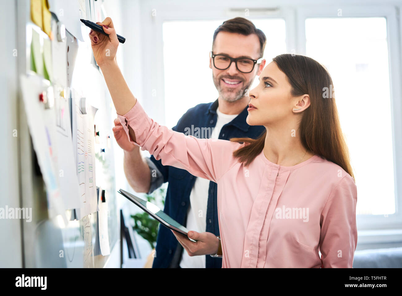 Two colleagues discussing at whiteboard in office Stock Photo - Alamy