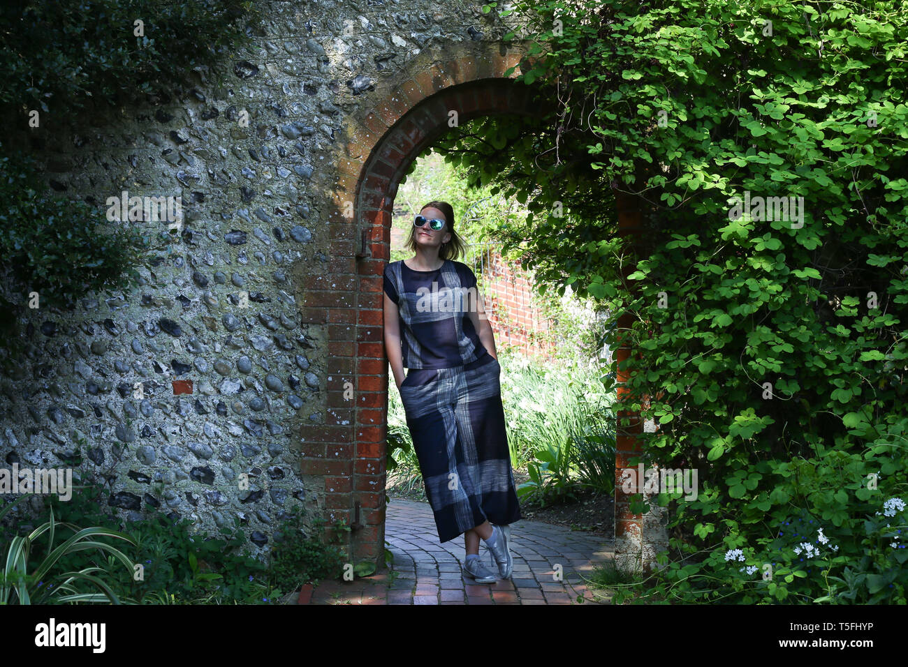 a young woman standing inside a brick arch in the Kipling gardens ...