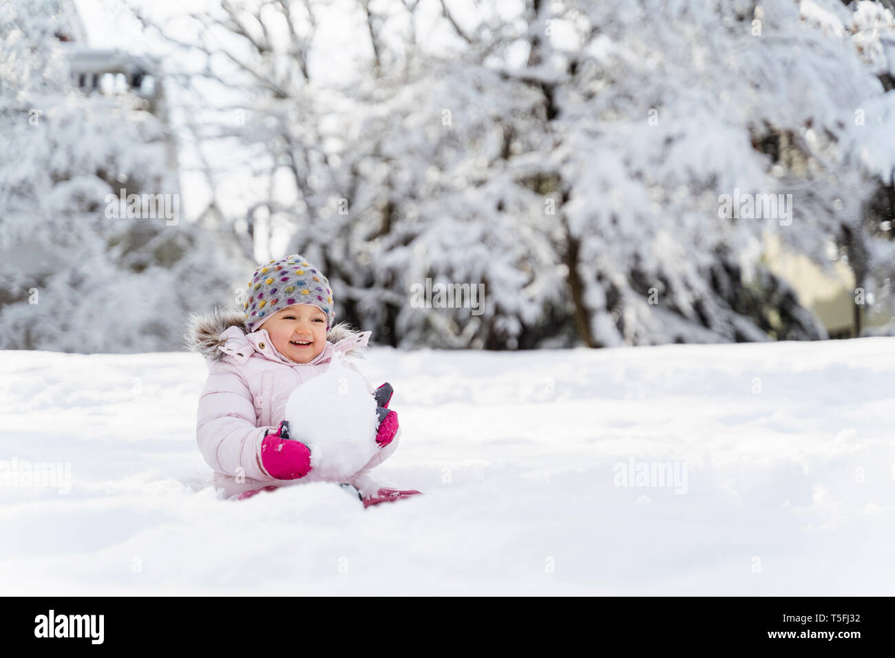Cute little girl playing with snow in winter Stock Photo - Alamy