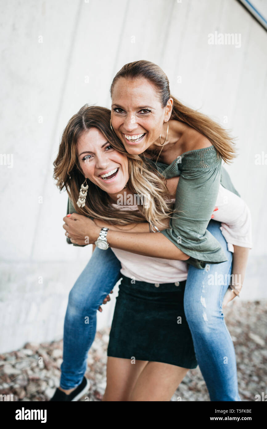 Portrait of laughing woman giving her friend a piggyback ride Stock ...