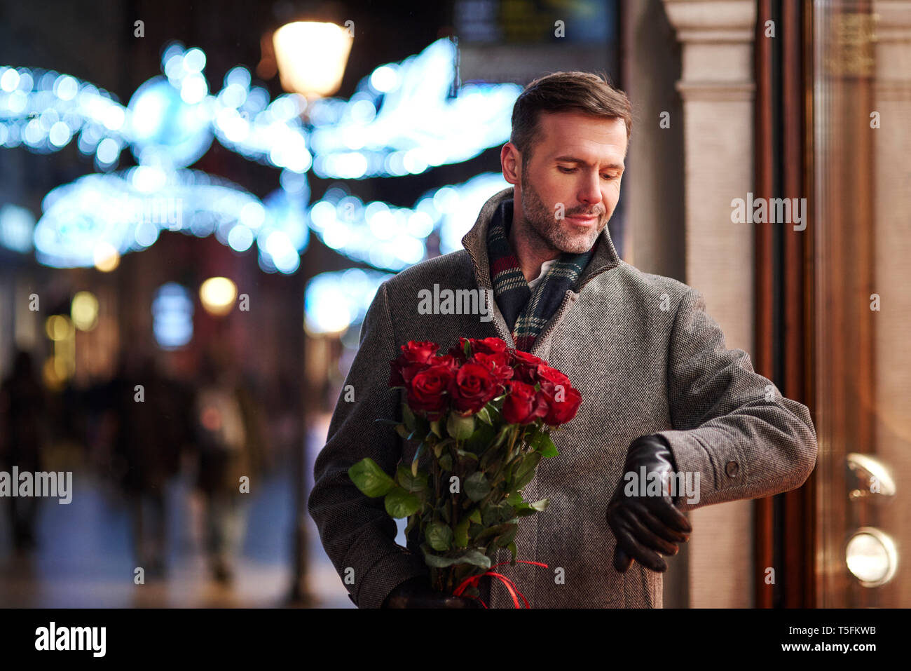 Portrait of waiting man with bunch of red roses checking the time Stock ...