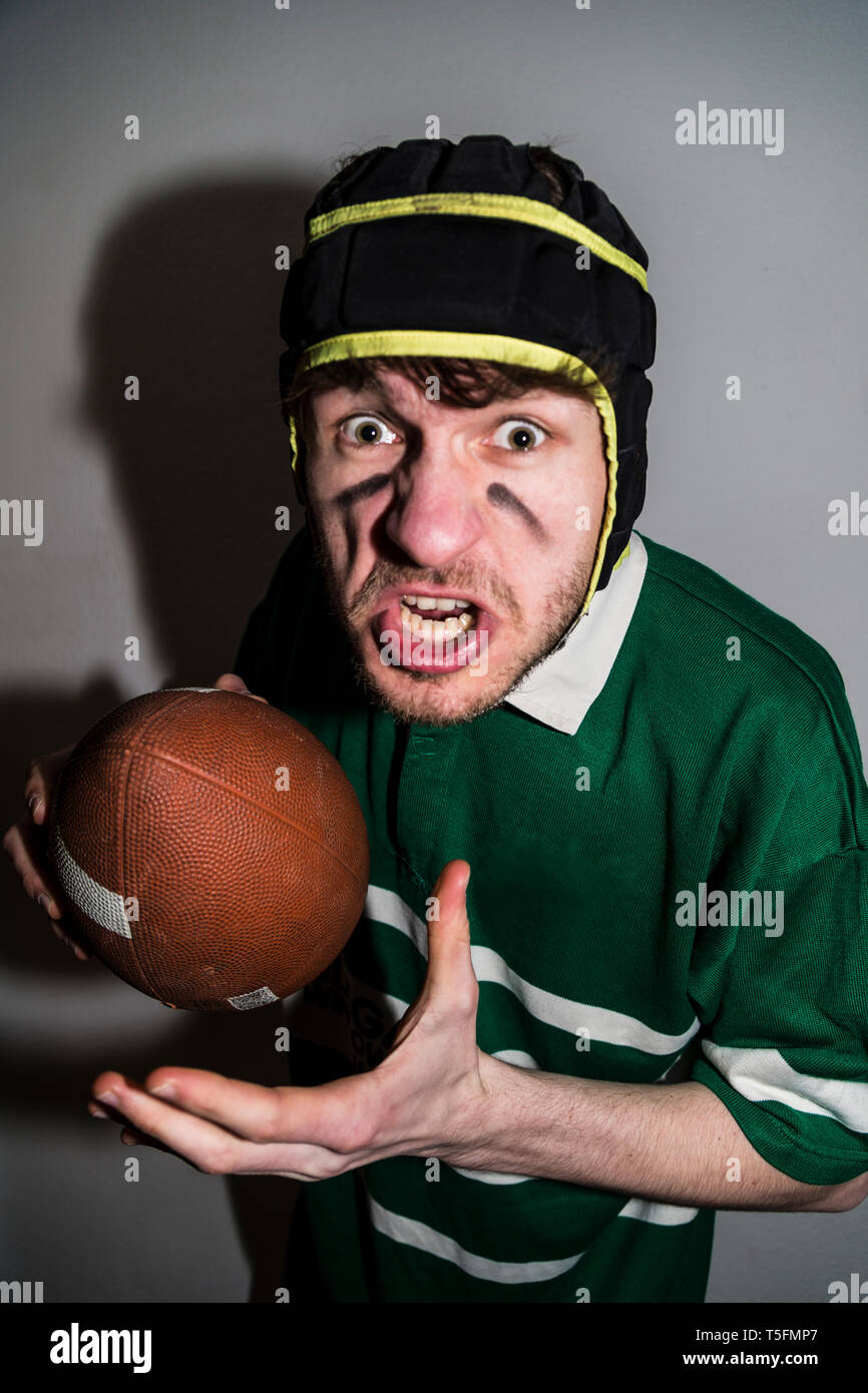Rugby player holding ball in hand and making faces Stock Photo - Alamy