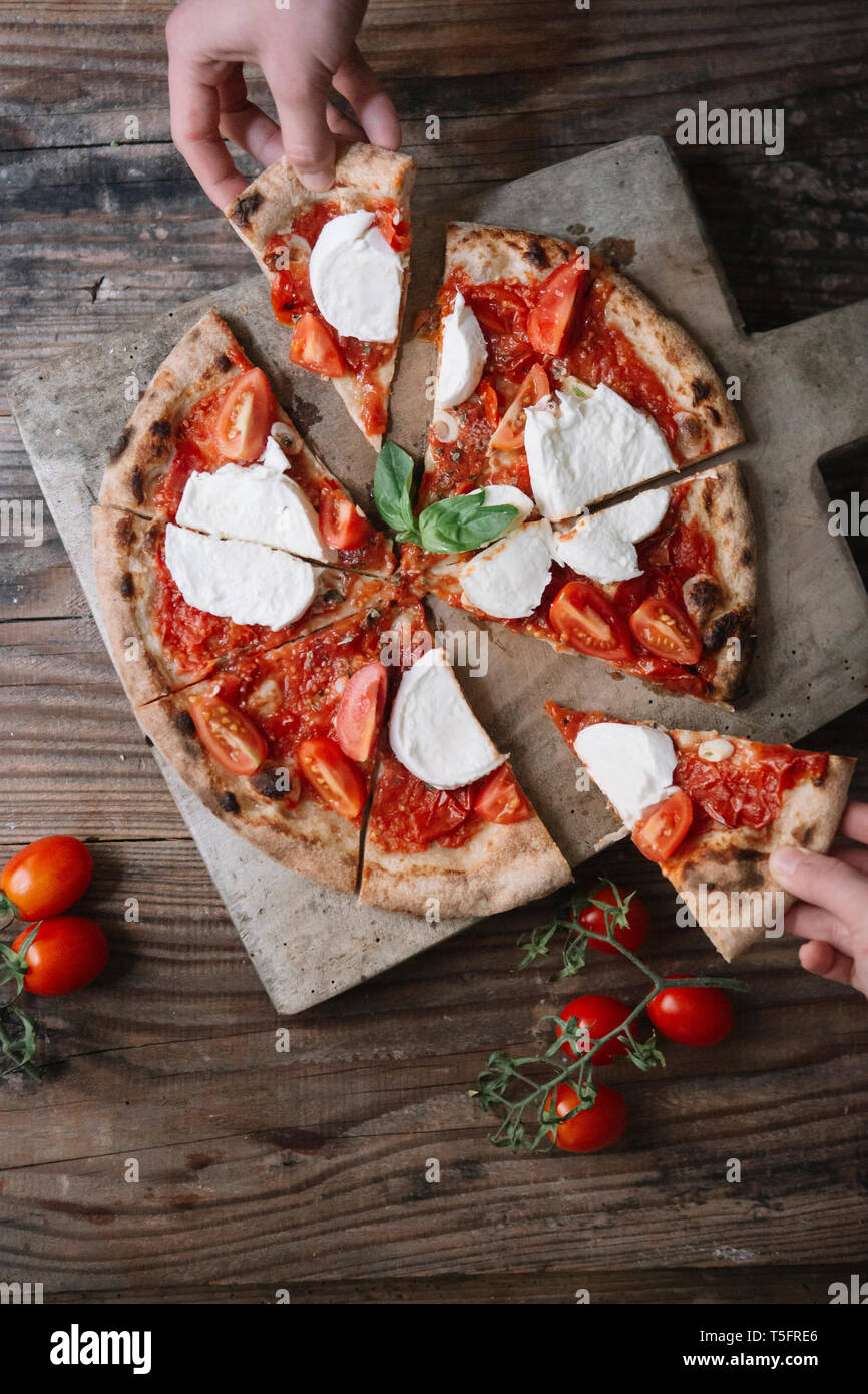 Eating a pizza with mozzarella, hand taking pizza slice Stock Photo - Alamy