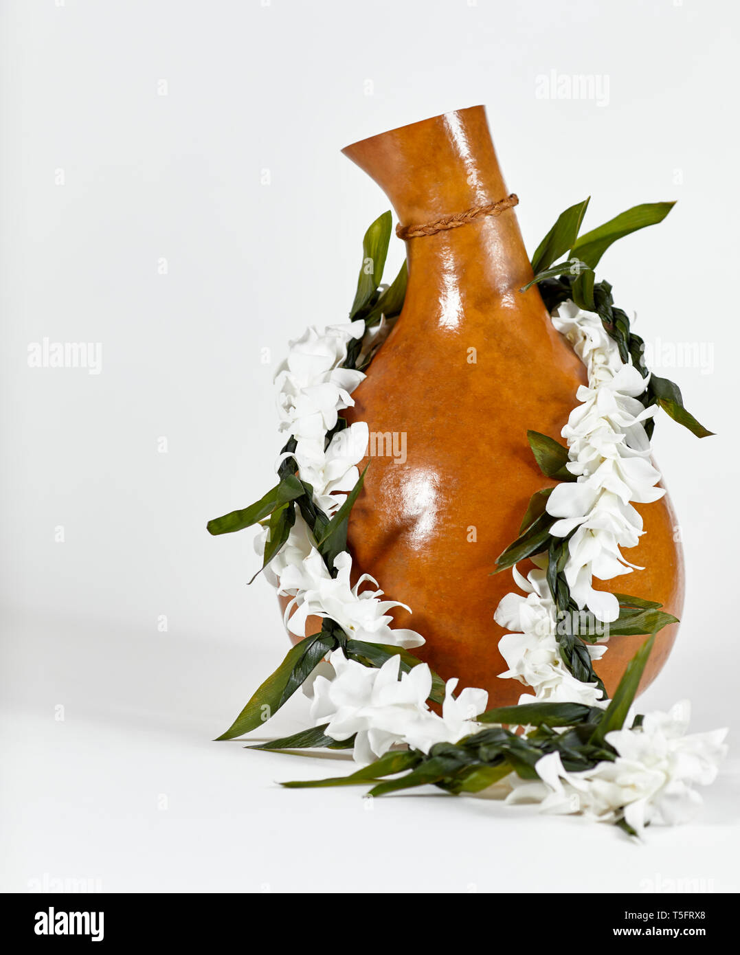 White flower Hawaiian lei with green twisted ti leaf lei laying on an ...